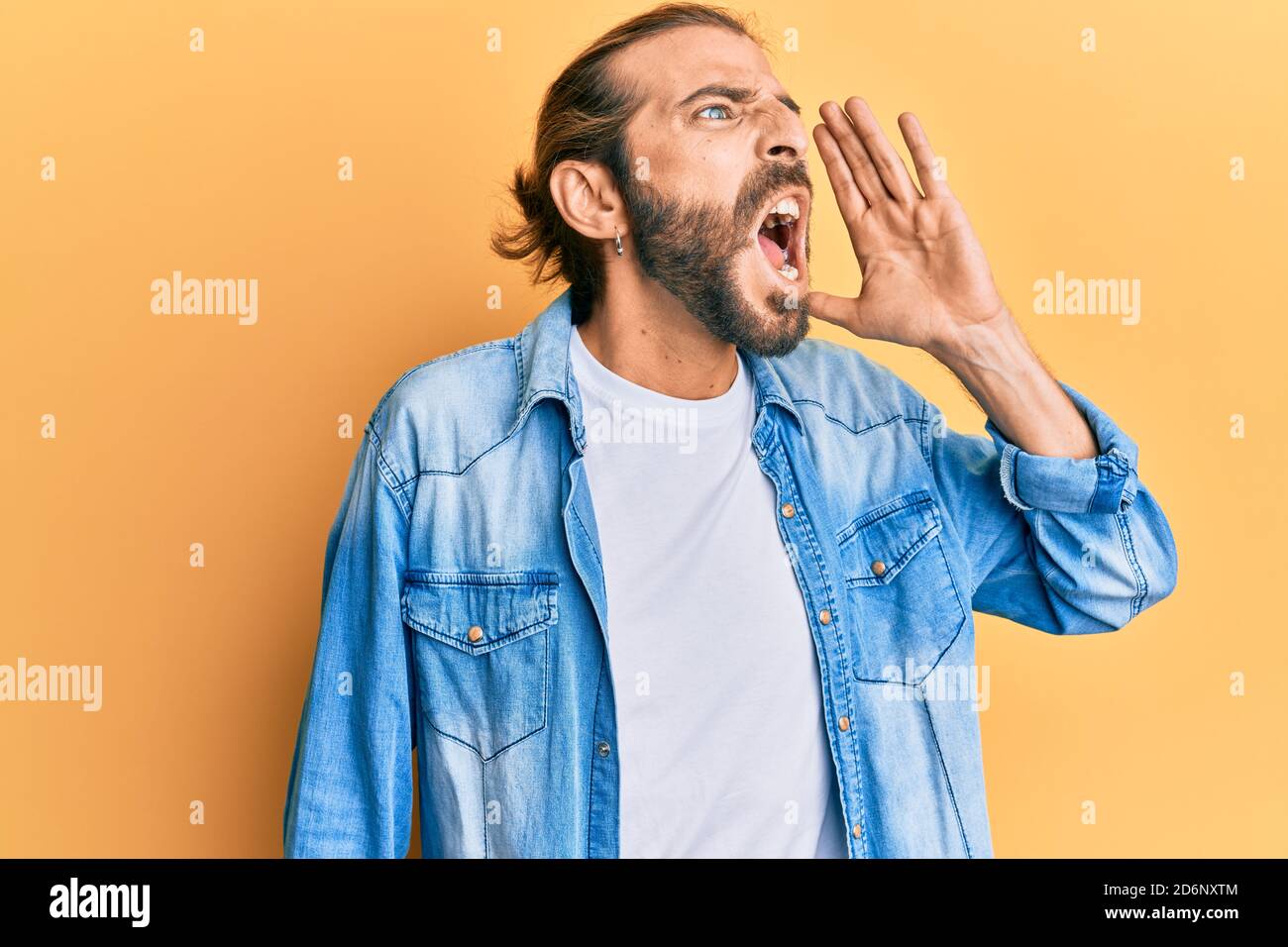 Attractive man with long hair and beard wearing casual denim jacket ...