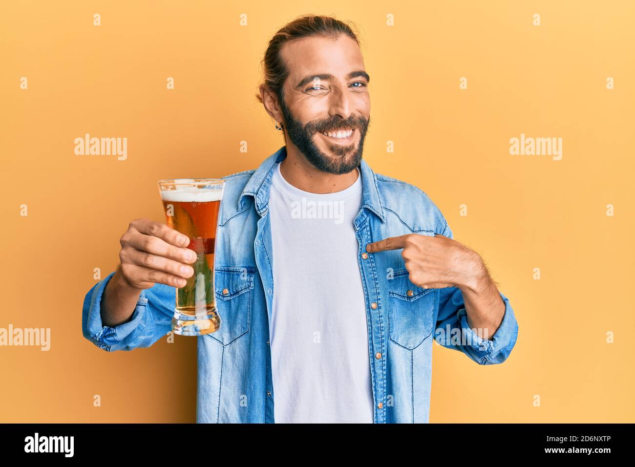 Attractive man with long hair and beard drinking a pint of beer ...