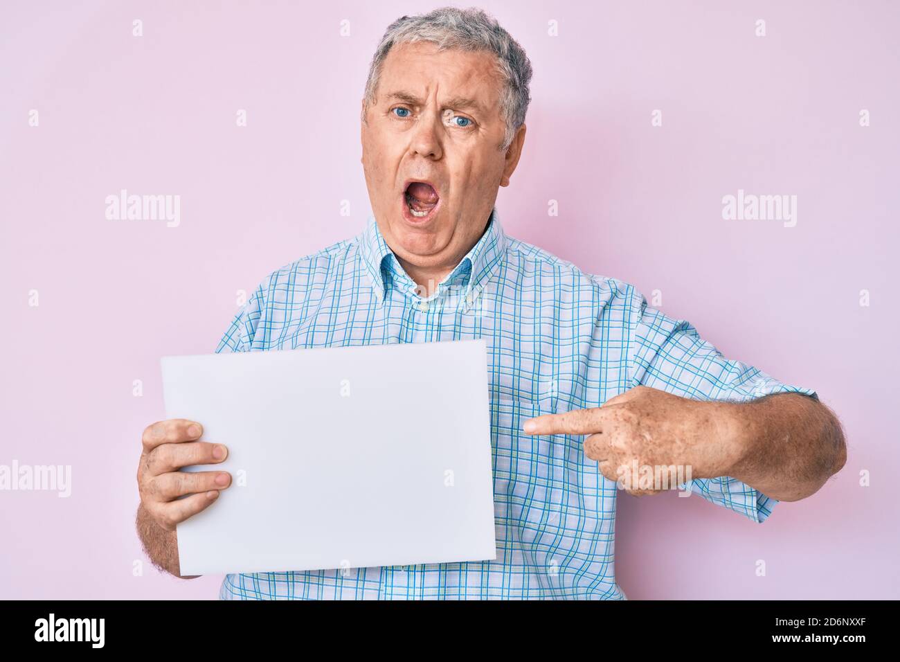 Senior grey-haired man holding blank empty banner angry and mad ...