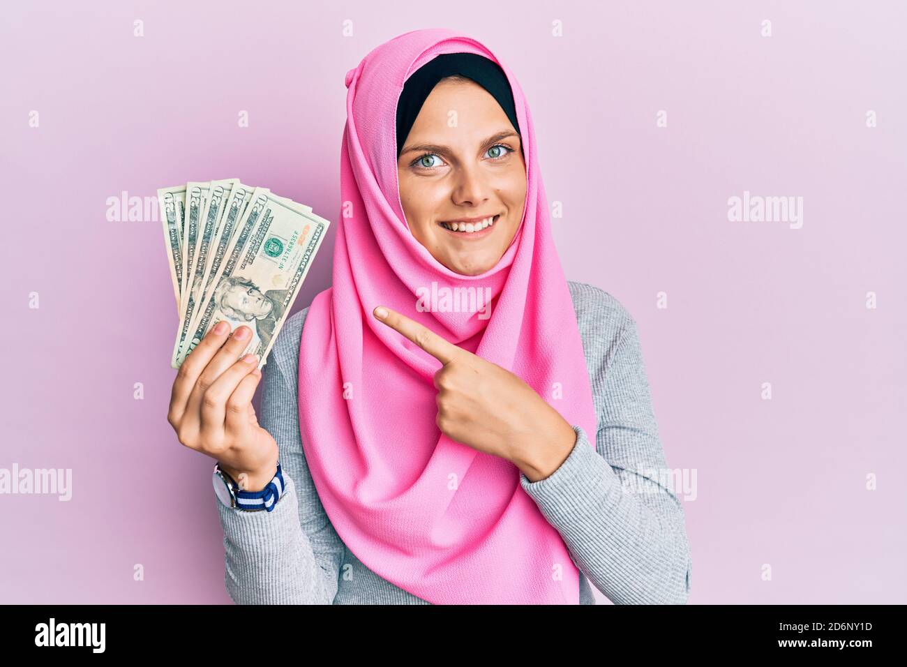 Young caucasian woman wearing islamic hijab holding 20 dollars ...