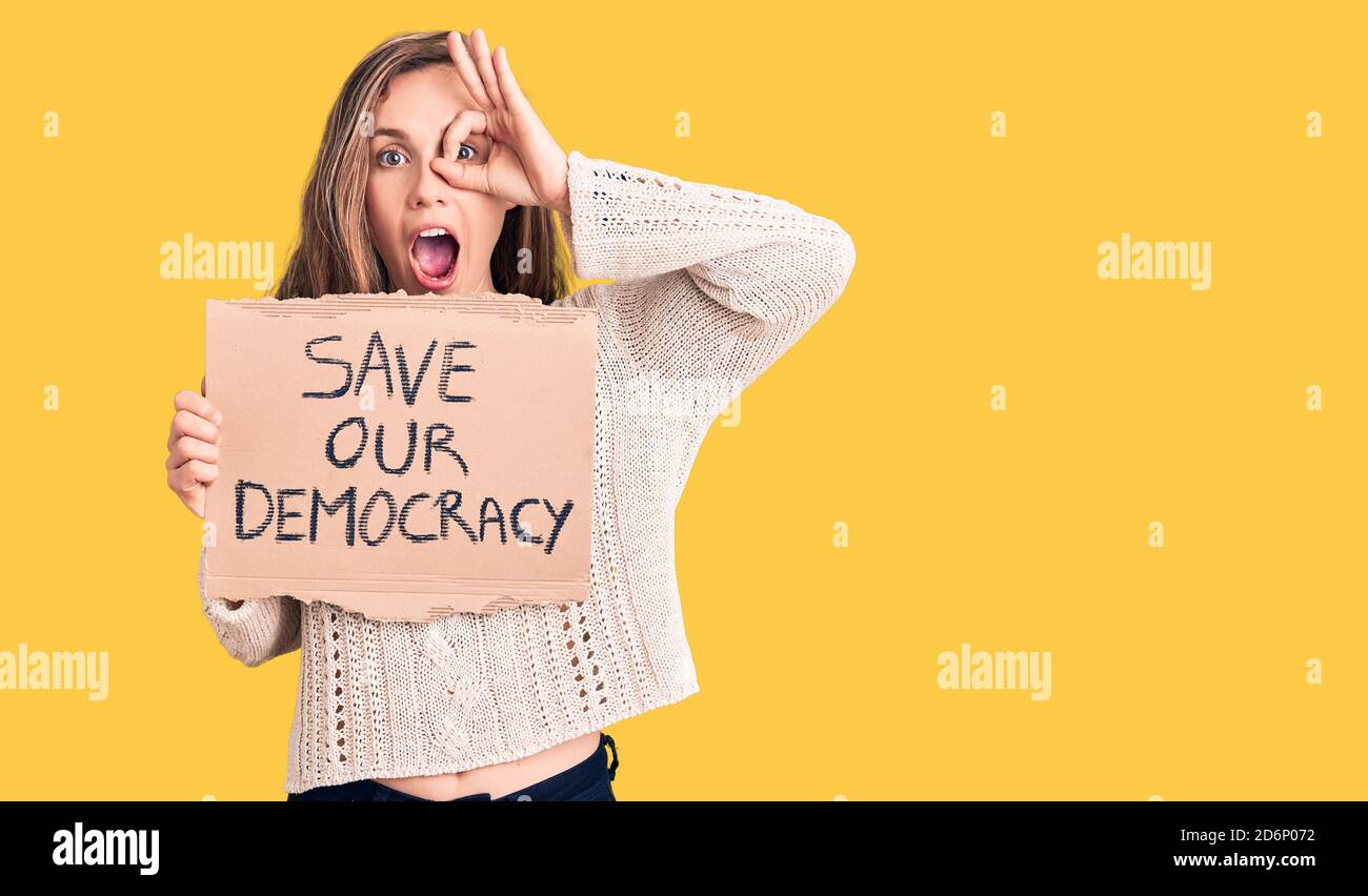 Young beautiful blonde woman holding save our democracy banner smiling ...