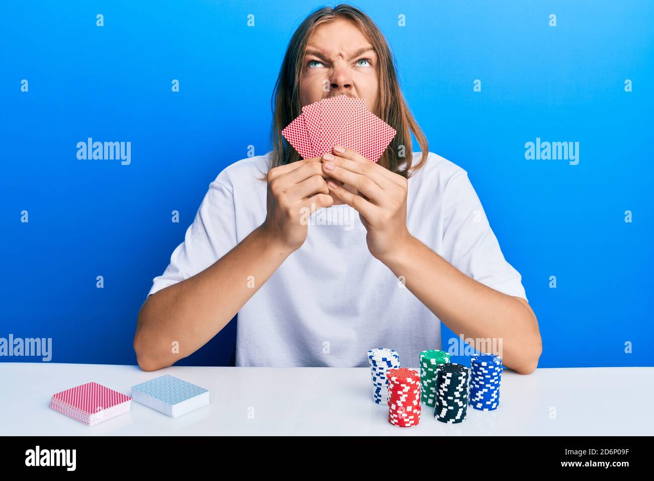 Handsome caucasian man with long hair playing gambling poker covering ...
