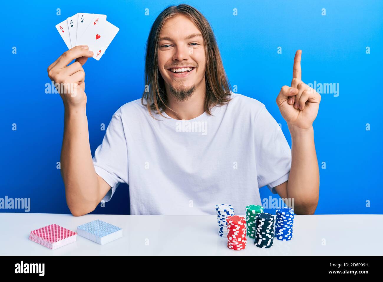 Handsome caucasian man with long hair playing poker holding cards ...