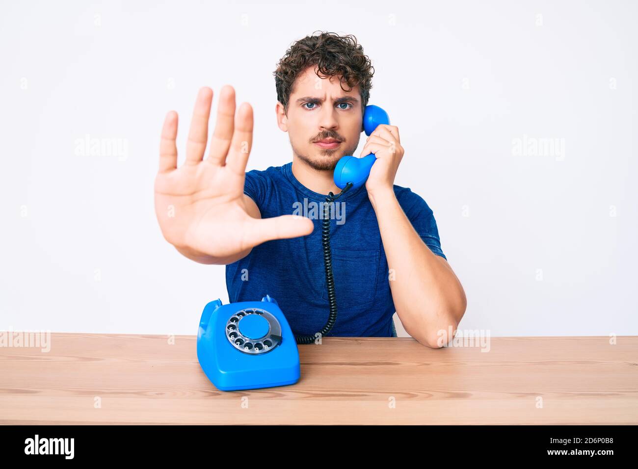 Young caucasian man with curly hair using vintage telephone sitting on ...