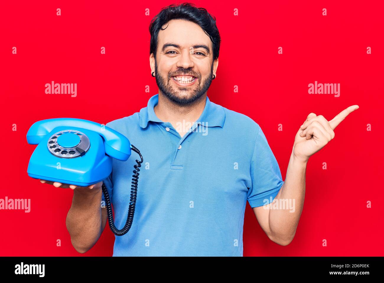 Young hispanic man holding vintage telephone smiling happy pointing ...