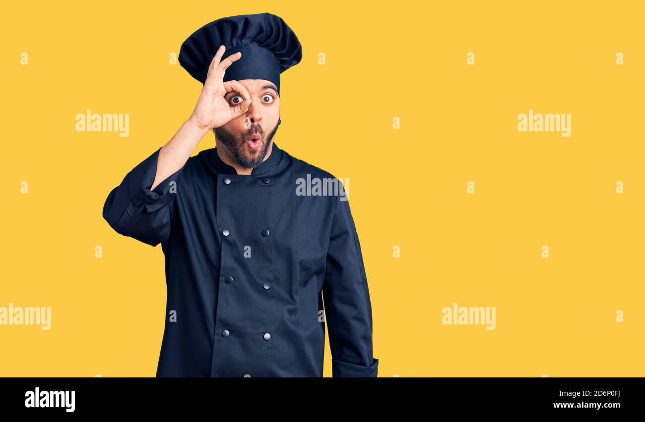 Young hispanic man wearing cooker uniform doing ok gesture shocked with ...