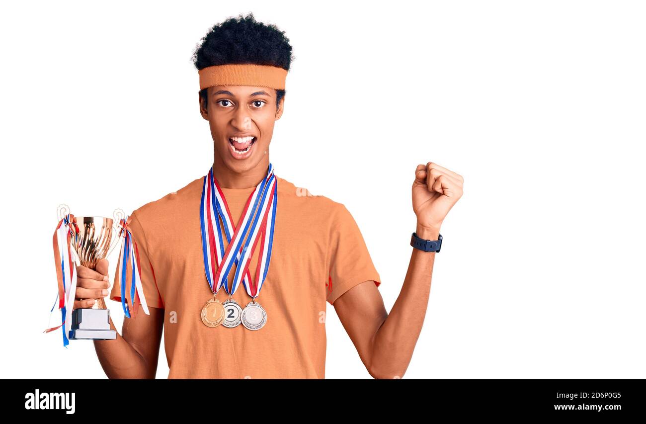 Young african american man holding champion trophy wearing medals ...