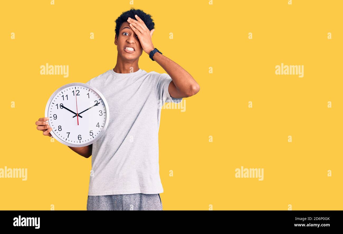 Young african american man holding big clock stressed and frustrated ...