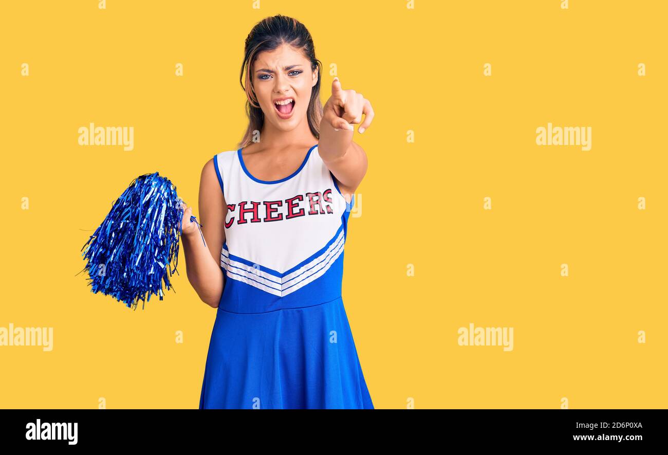 Young beautiful woman wearing cheerleader uniform pointing displeased ...