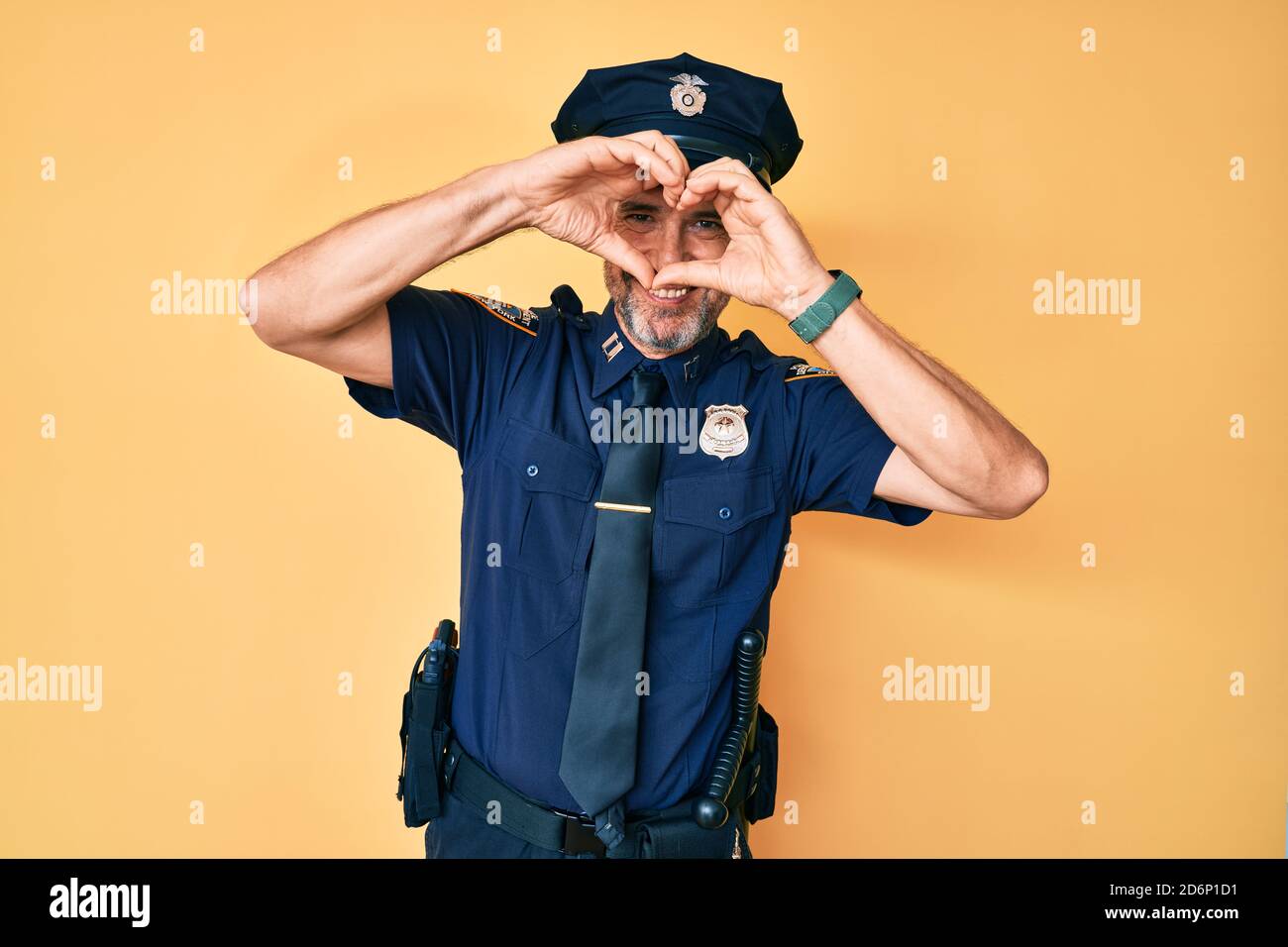 Middle age hispanic man wearing police uniform doing heart shape with ...