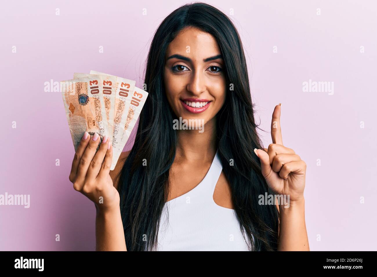 Beautiful hispanic woman holding united kingdom 10 pounds smiling with ...