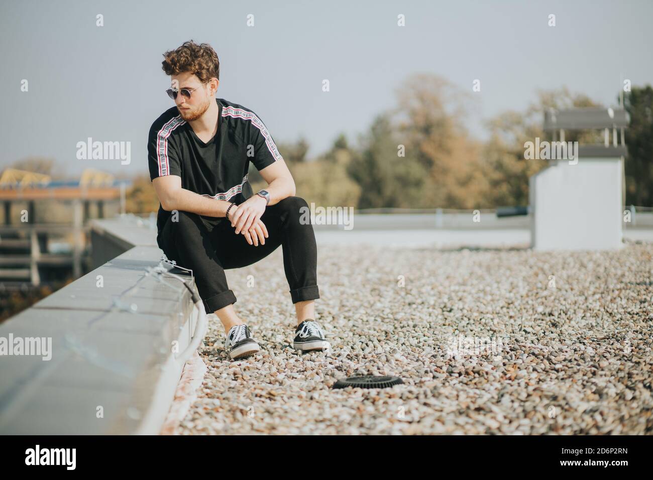 Closeup of a young Caucasian male sitting on the rooftop and looking ...