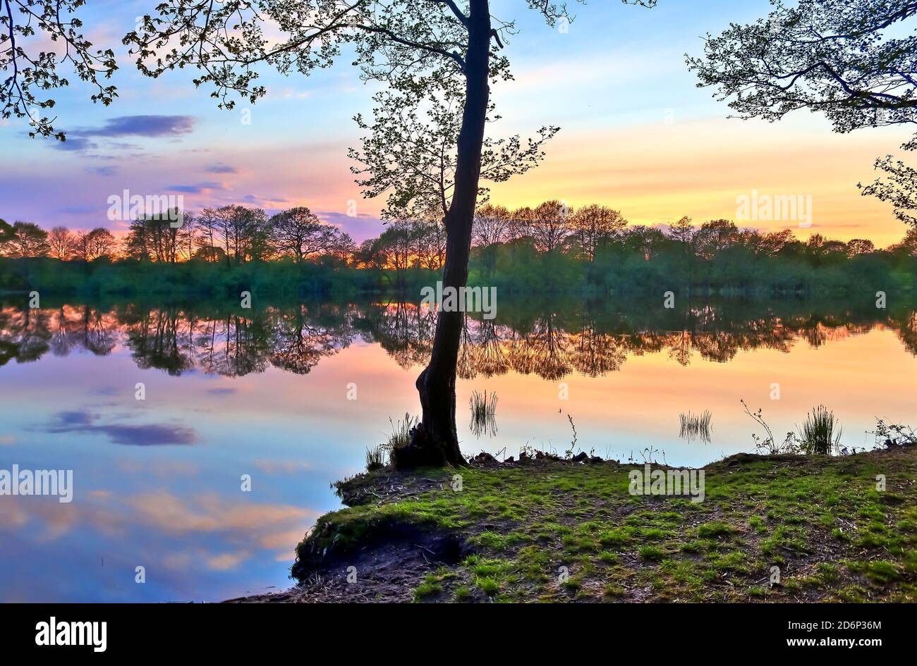 Beautiful sunset landscape at a lake with a reflective water surface ...