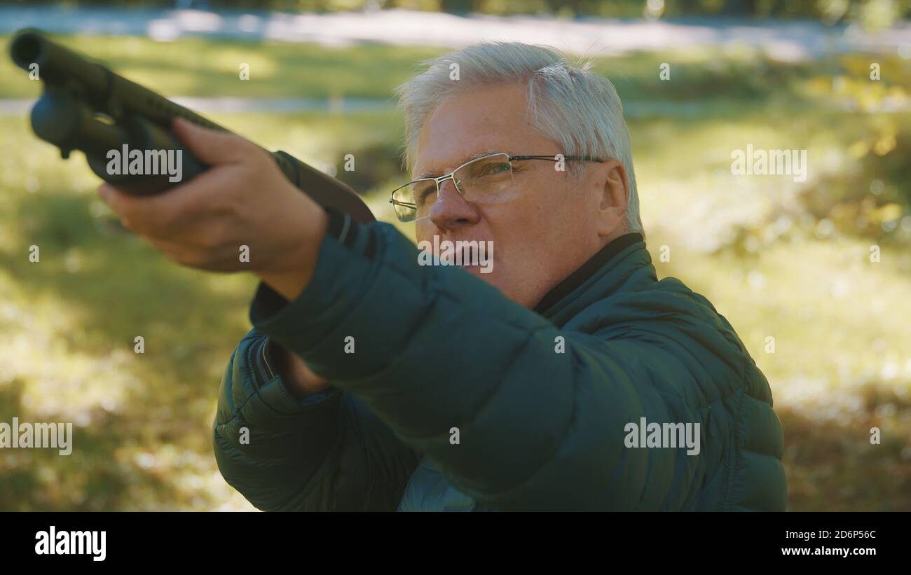 Elderly gray haired man holding a gun in his hands. War or revolution ...