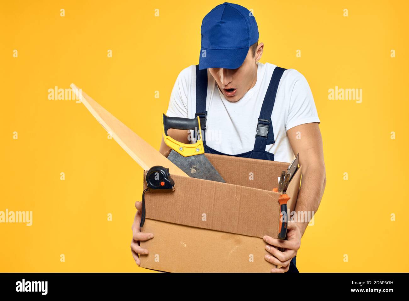 worker with box in hand tools loader yellow background Stock Photo - Alamy