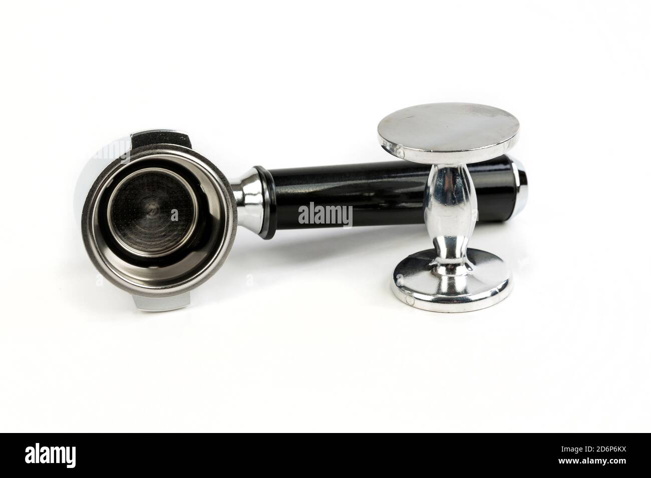 Black and silver coffee filter holder on its side by a metal tamper ...