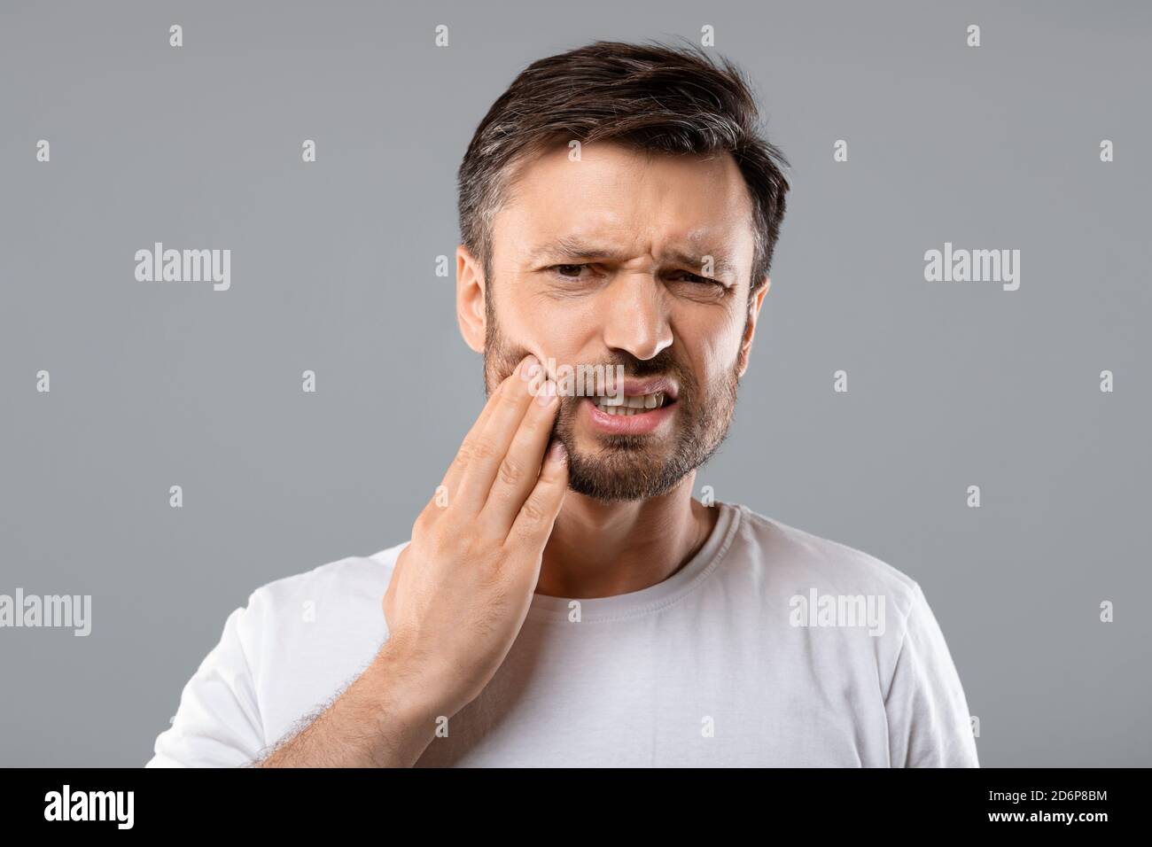 Man suffering from strong tooth pain, grey background Stock Photo - Alamy