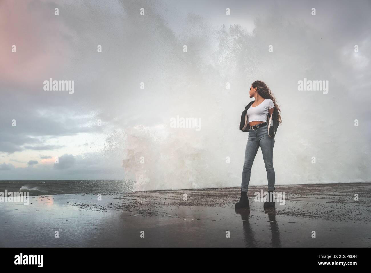 Young woman attending how the waves hit the rocks Stock Photo - Alamy