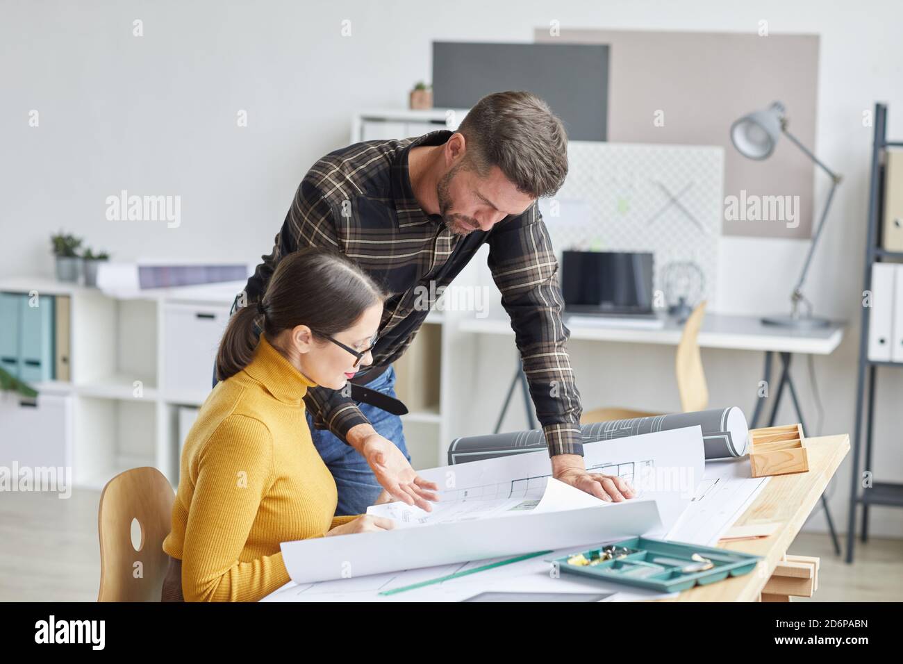 Side view portrait of two architects collaborating on blueprints while ...