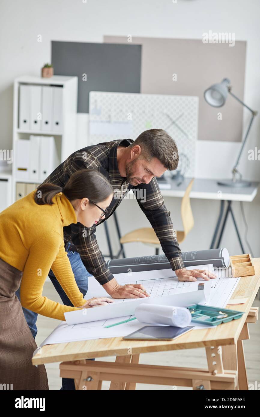 Vertical side view portrait of two architects cdrawing blueprints while ...