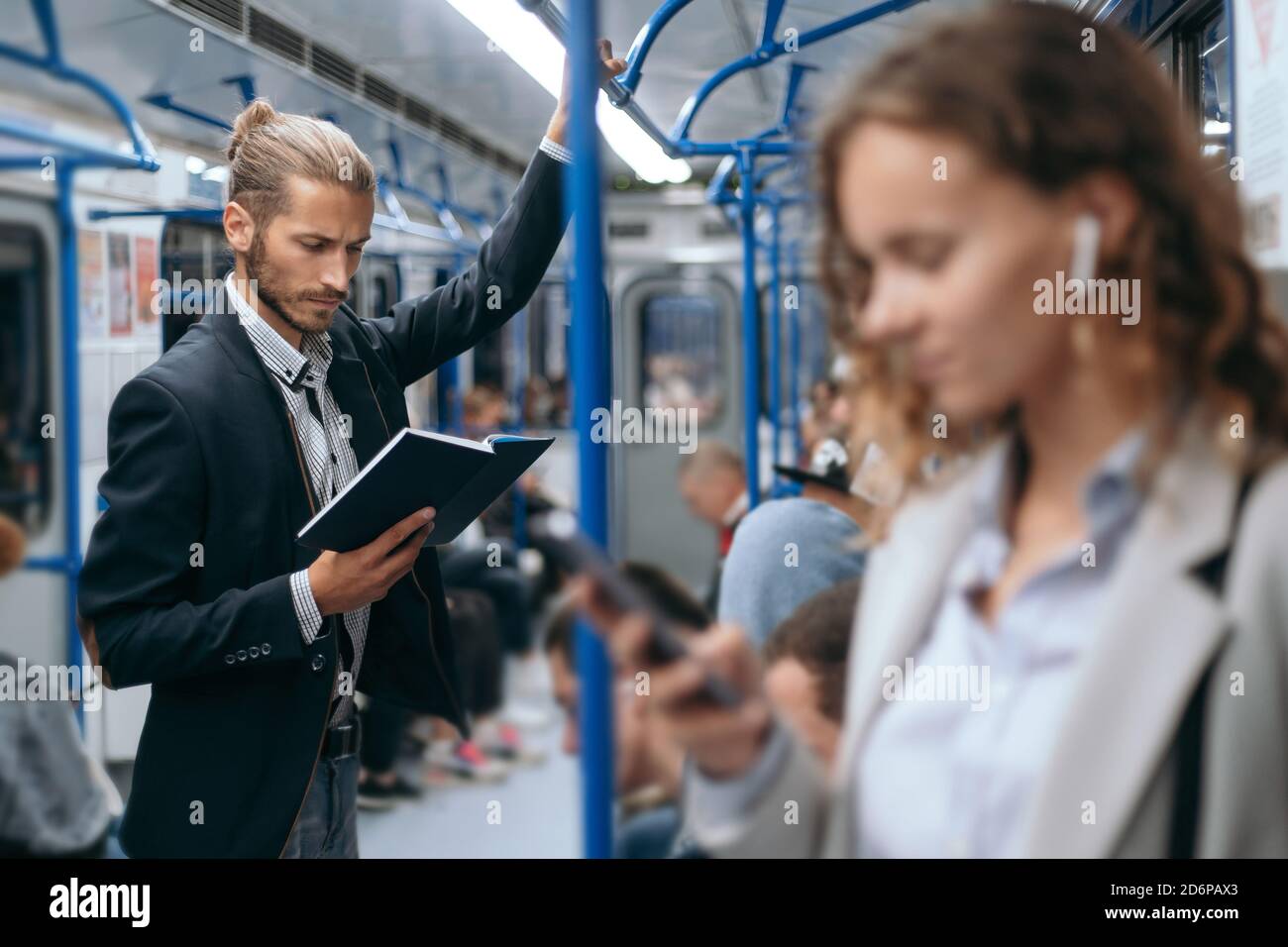 young man reading a book on a subway train Stock Photo - Alamy
