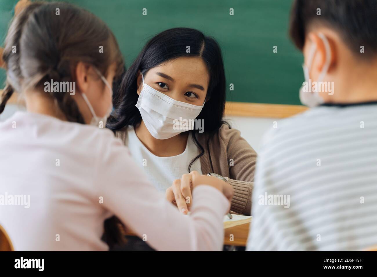 Close-up of Asian female teacher wearing a face mask in school building ...
