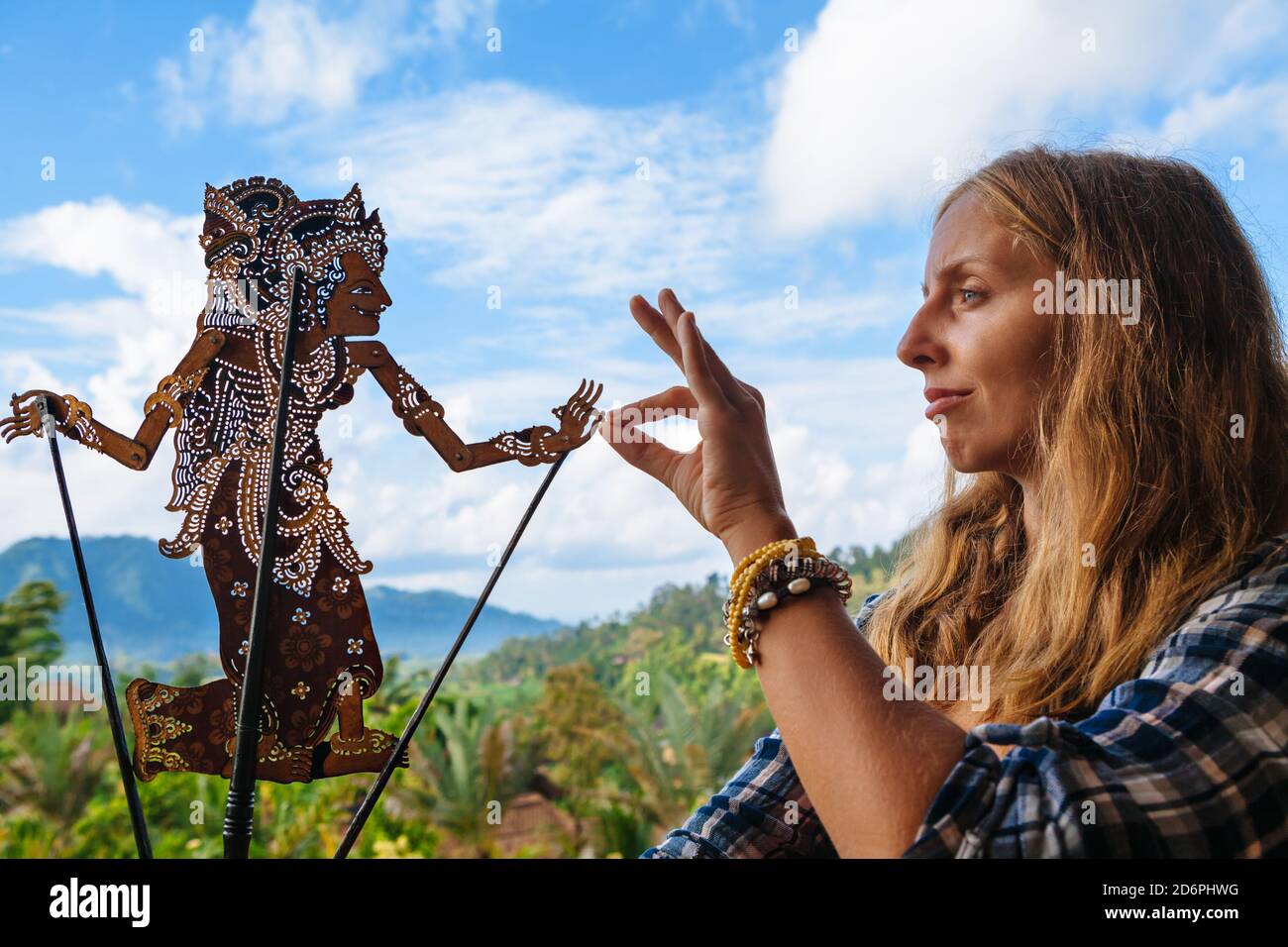 Woman holds in hand old traditional shadow puppet of Bali Island ...