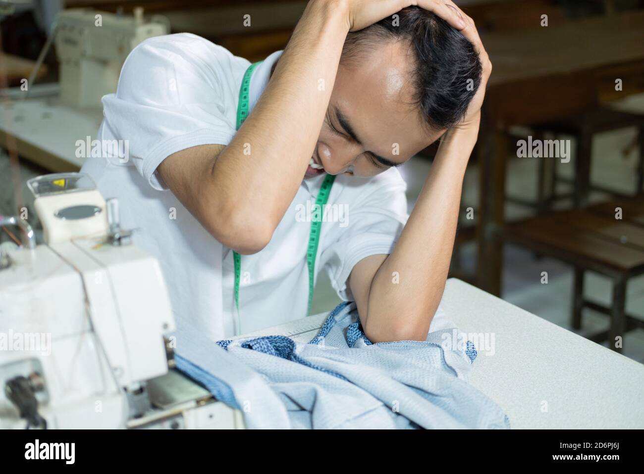 male seamstress looked down with her head feeling depressed while ...