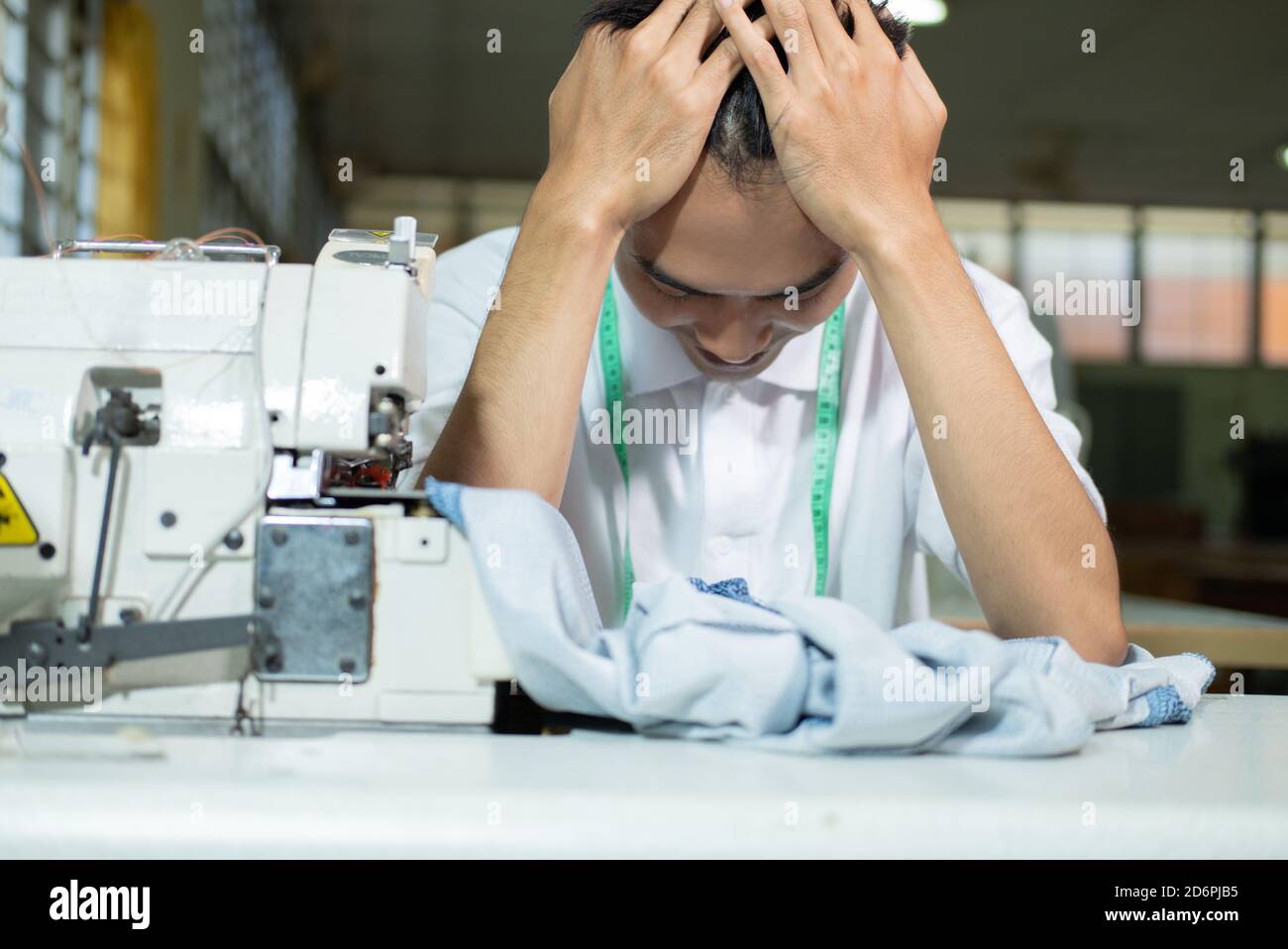 Asian male tailor are looking down with their hand on their head while ...