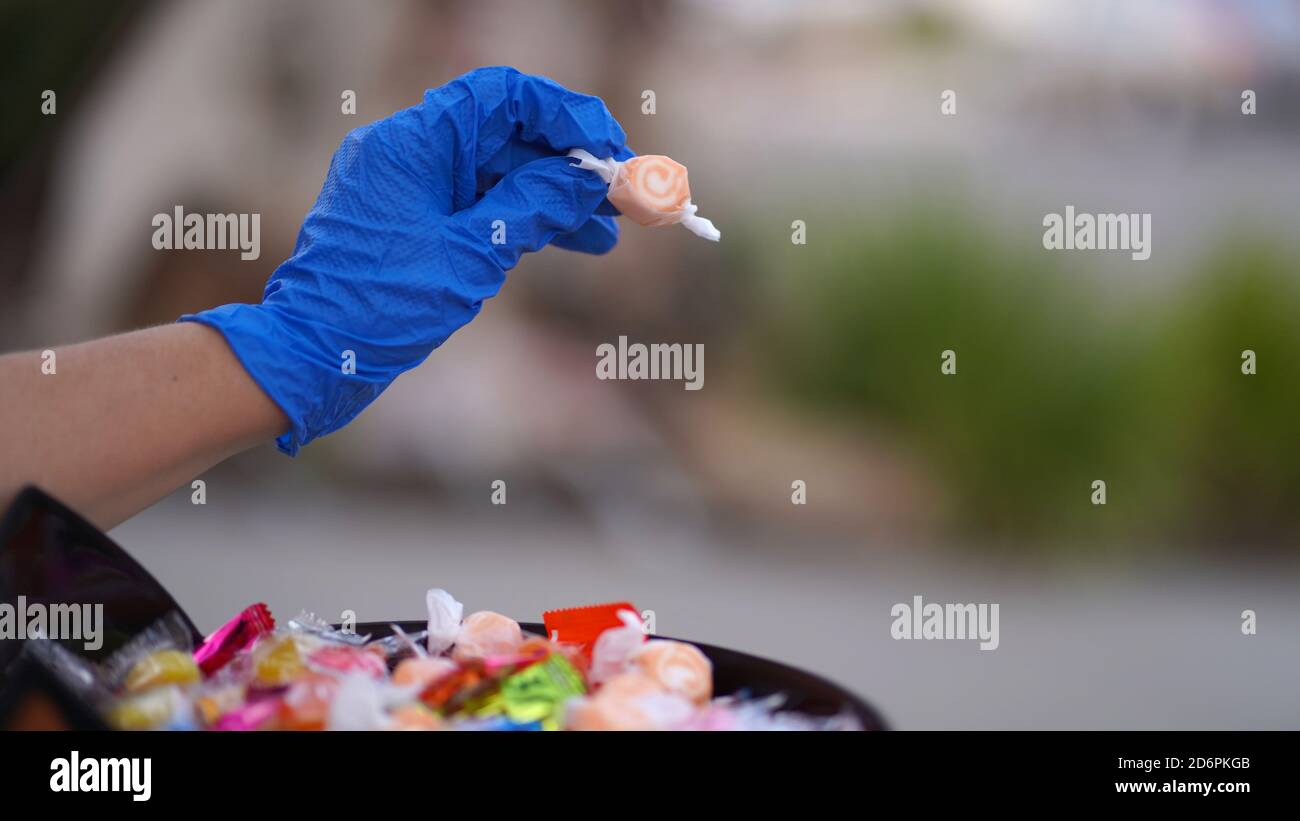 Halloween 2020: close-up of a gloved hand giving out candy in times of ...