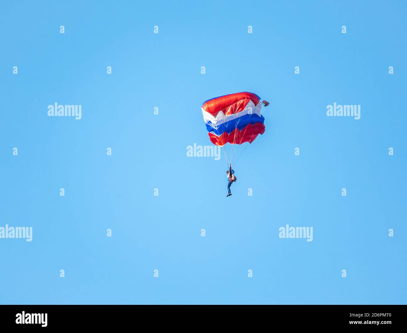 One parachutist floats slowly at low altitude on the background of ...