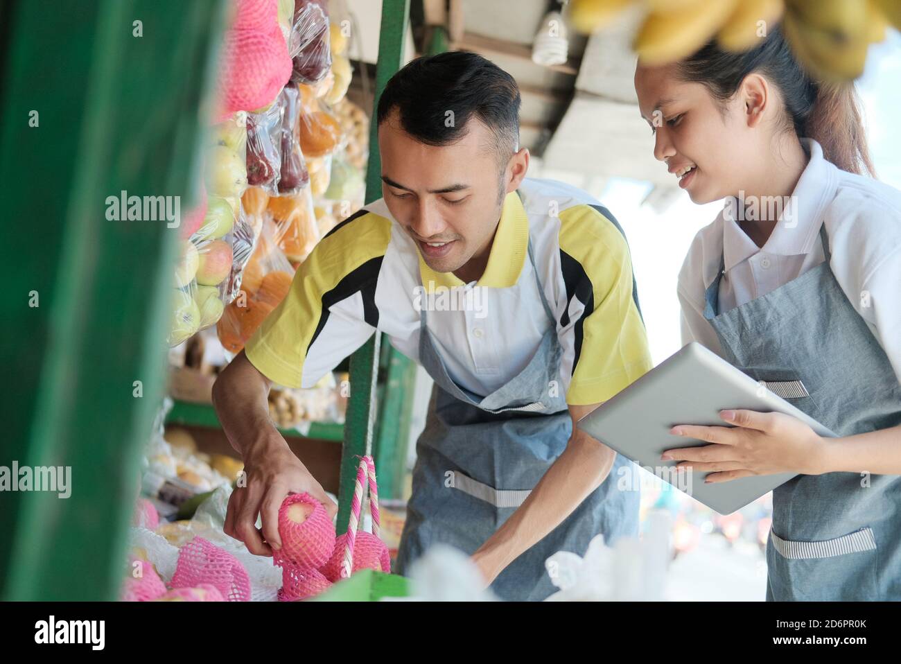 asian young man and woman worker stands front a display rack fruits ...