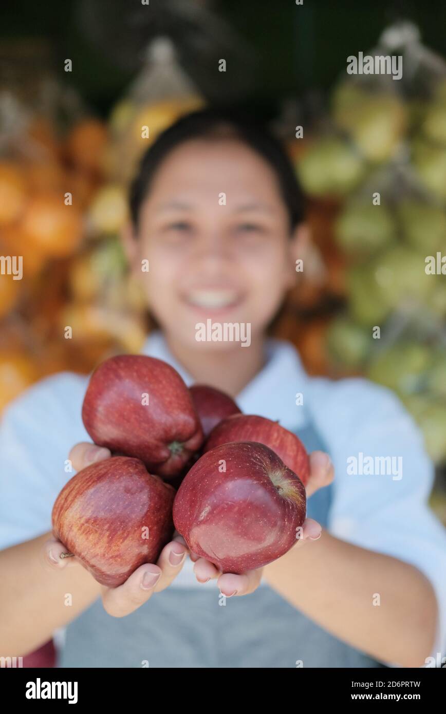 Fresh red apples in the hands of a fruit shop clerk at a fruit stand ...