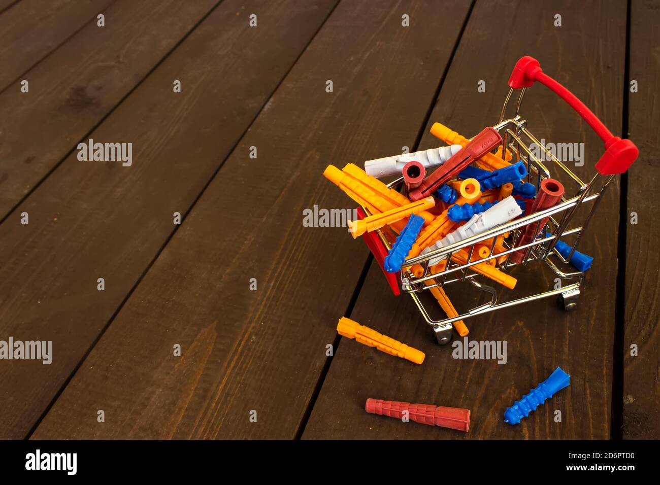 Miniature red shopping cart model with plastic dowels on wood ...