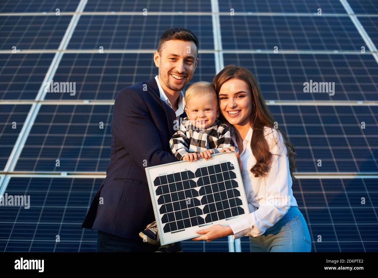 Portrait of a young family holding a small solar panel and a baby boy ...