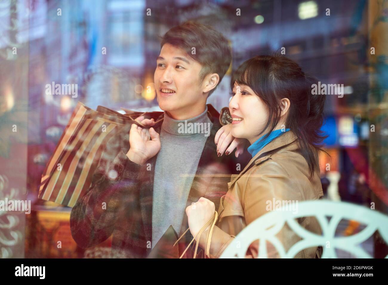 happy young asian couple looking into shop window in modern city Stock ...