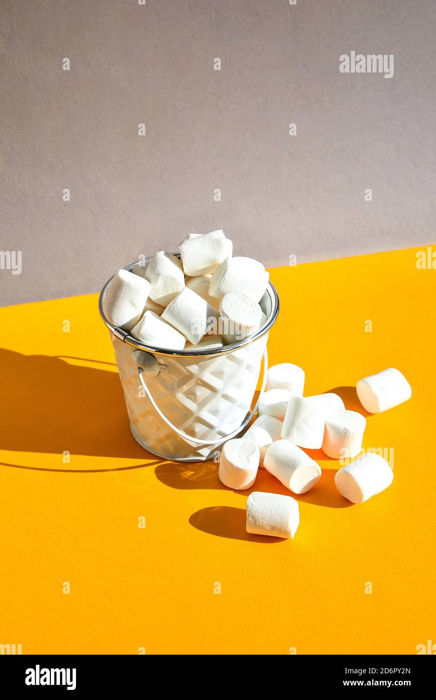 White marshmallows in metal bucket on a yellow and grey modern ...