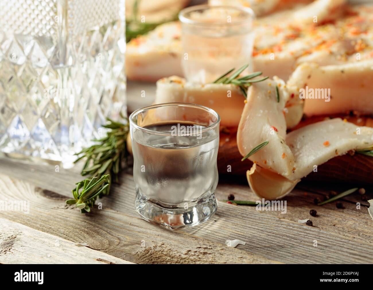 Frozen glass with cold vodka and slices of spicy salted lard. Lard with ...