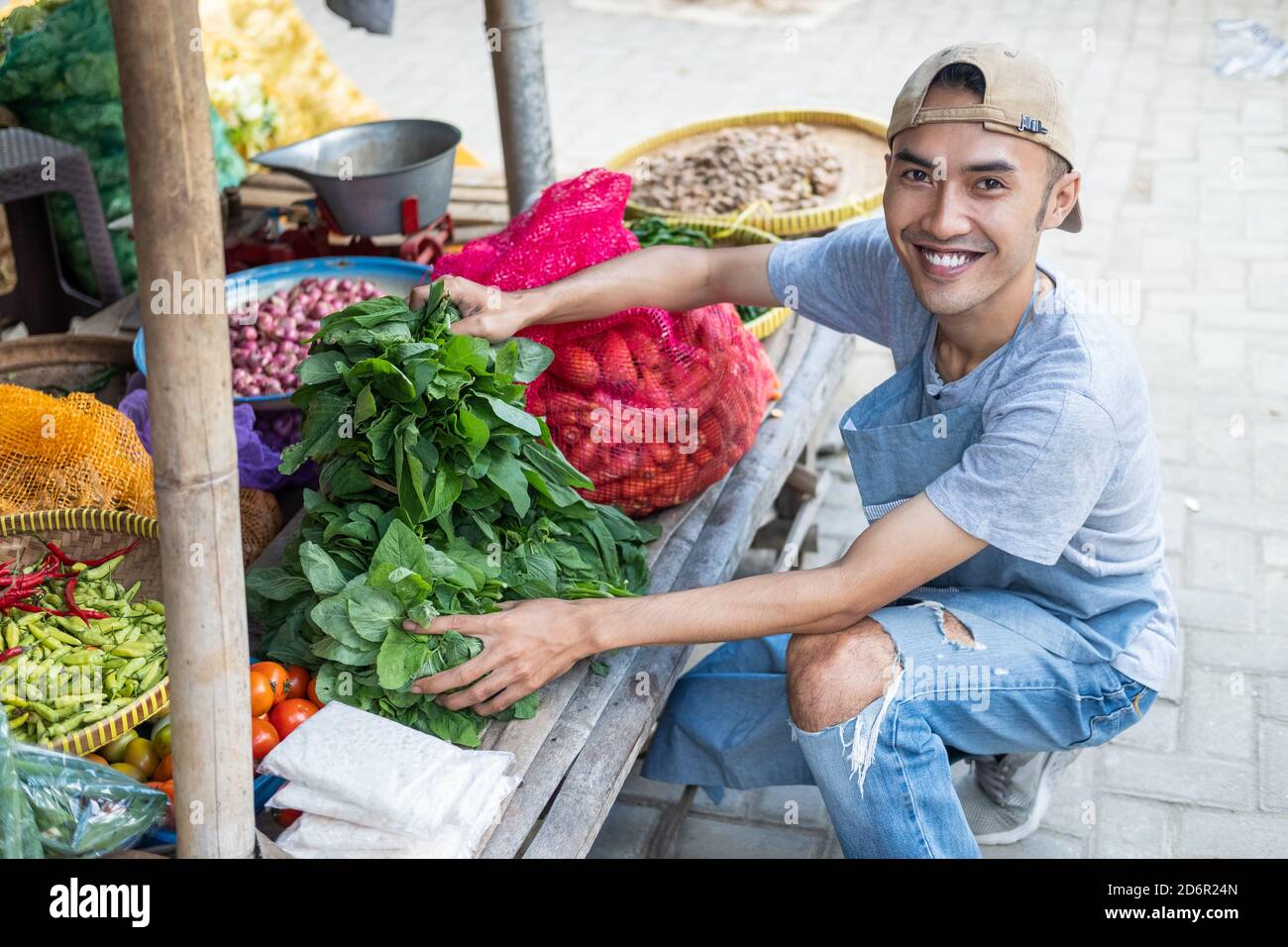Vegetable stall sales man smiles while holding spinach vegetables in ...