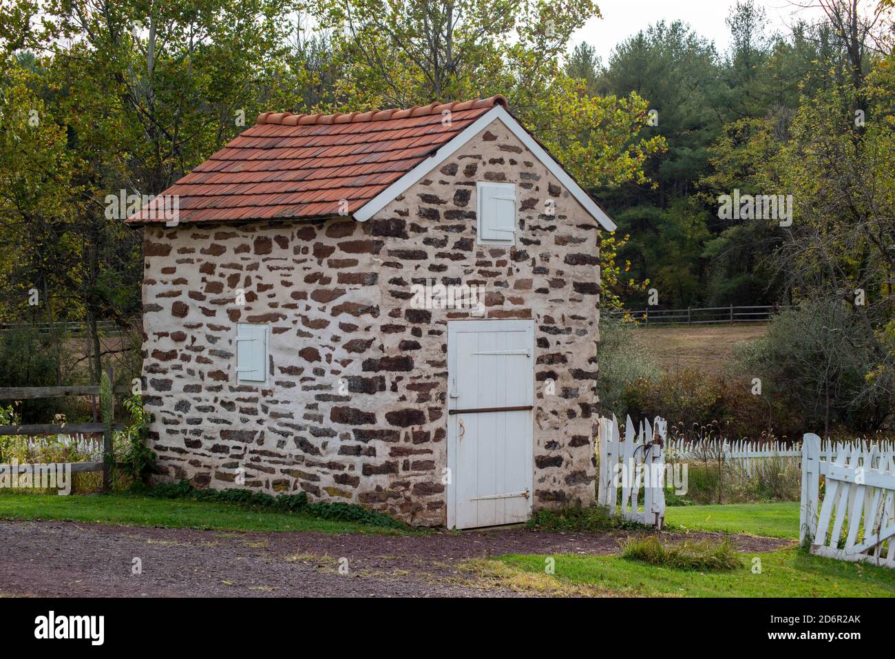Colonial stone spring house with wooden shutters by white garden gate ...