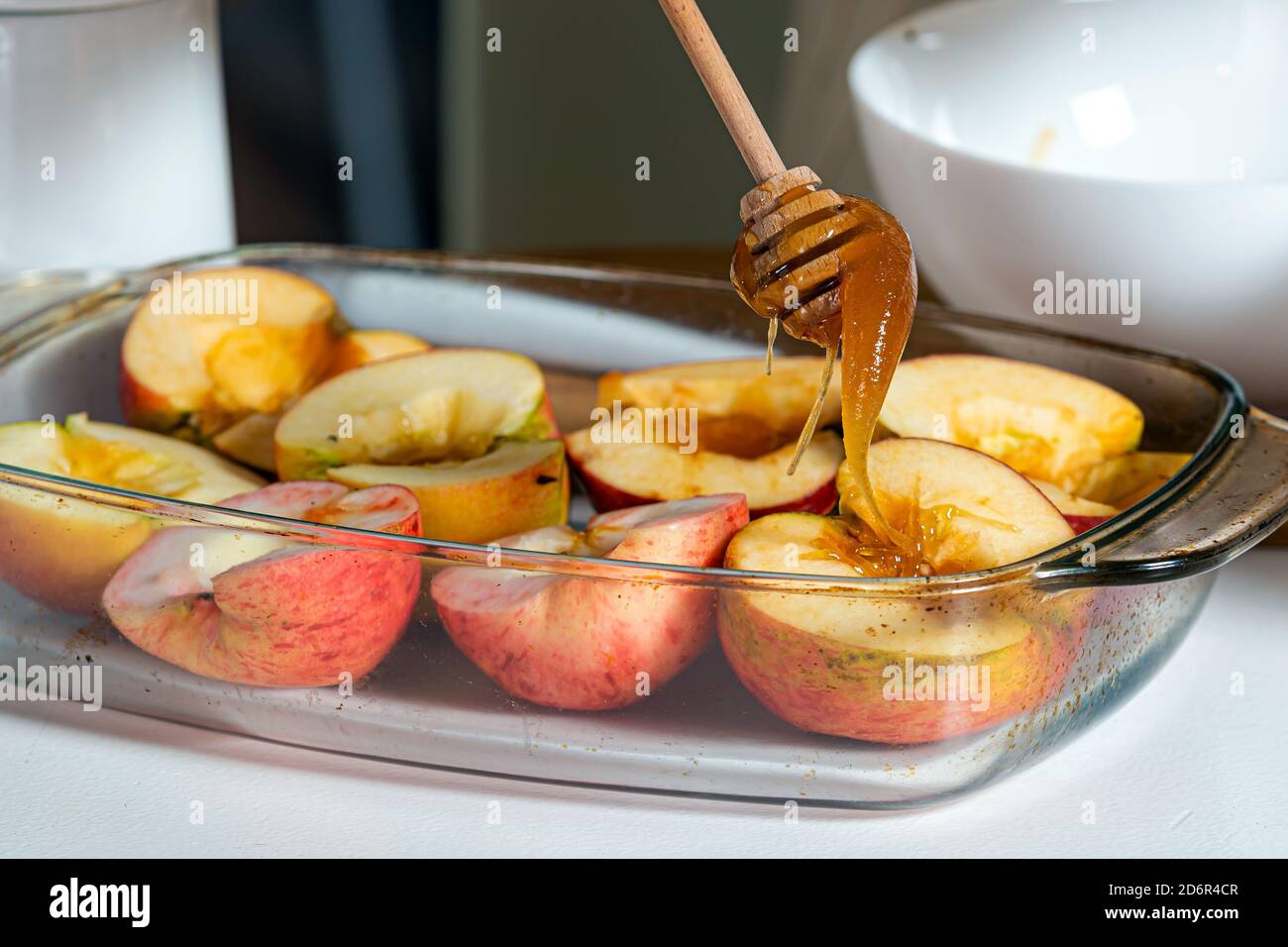 female hands with stick pouring apples with honey in a glass container ...