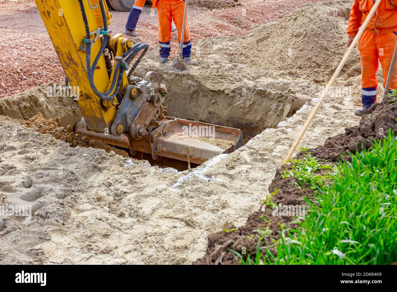 Low view on workers legs as they are waiting for excavator to finish ...