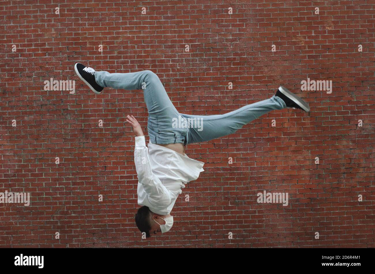 Stylish young man doing a flip wearing a sanitary mask-concept of the ...