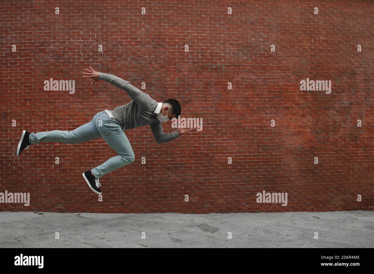 Athletic young man doing a jump wearing a sanitary mask-concept of the ...