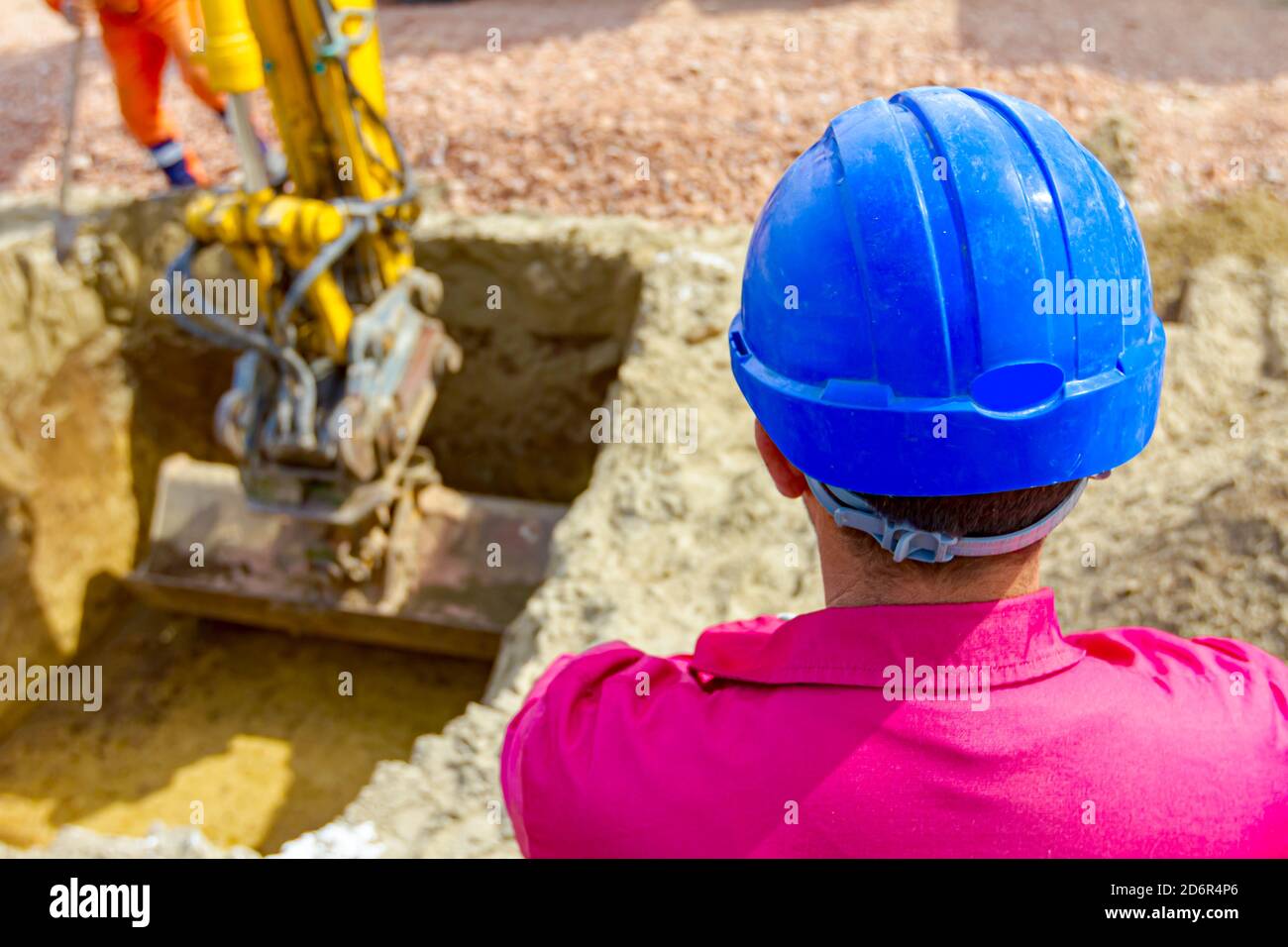 View from behind on construction worker, foreman, with safety blue ...