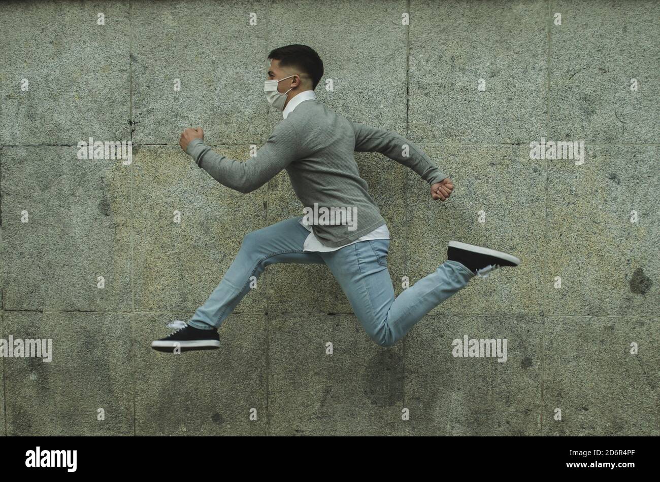 Athletic young man doing a jump wearing a sanitary mask-concept of the ...