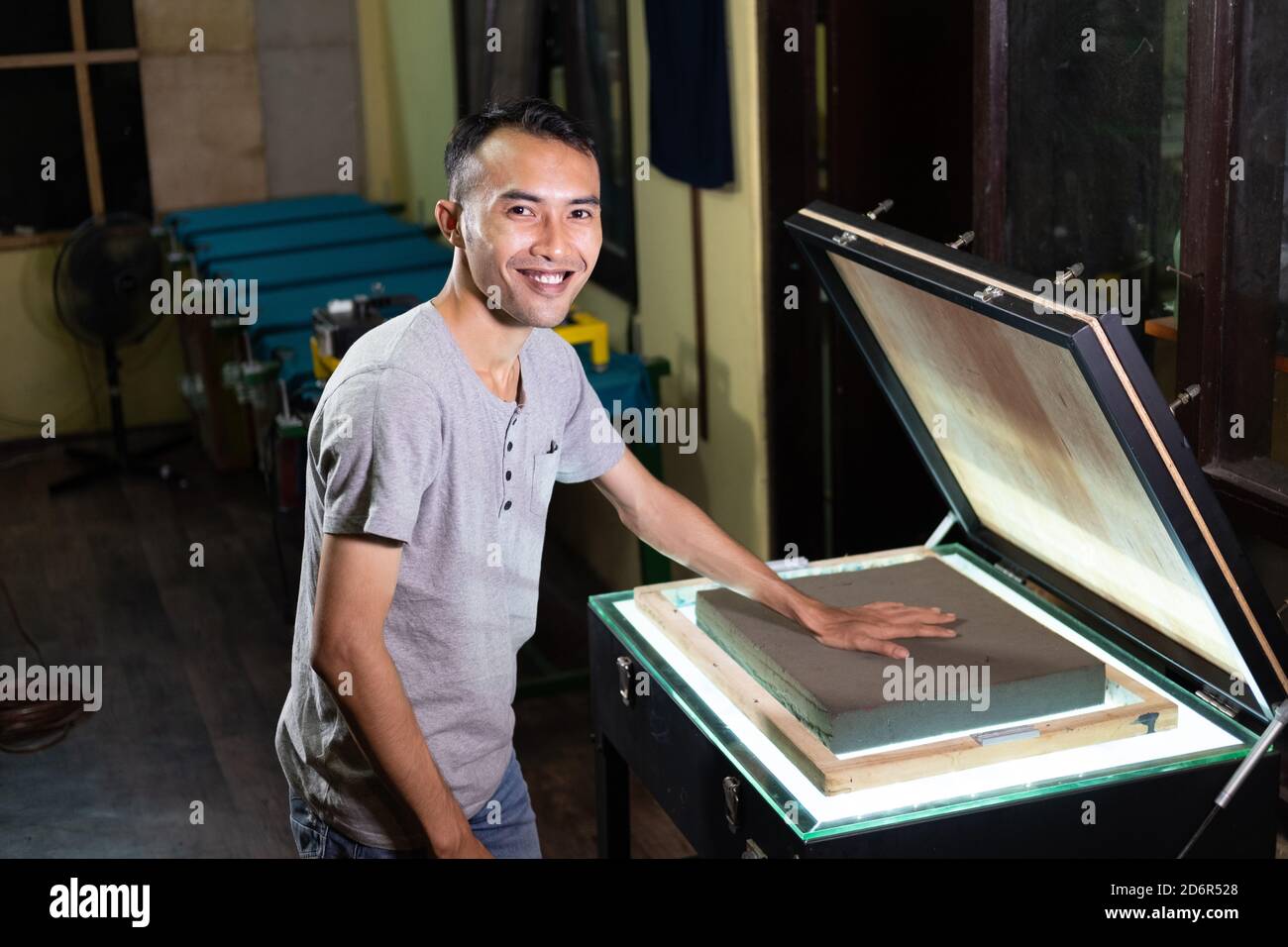 smiling man working to press a sponge to prepare make film on silk ...