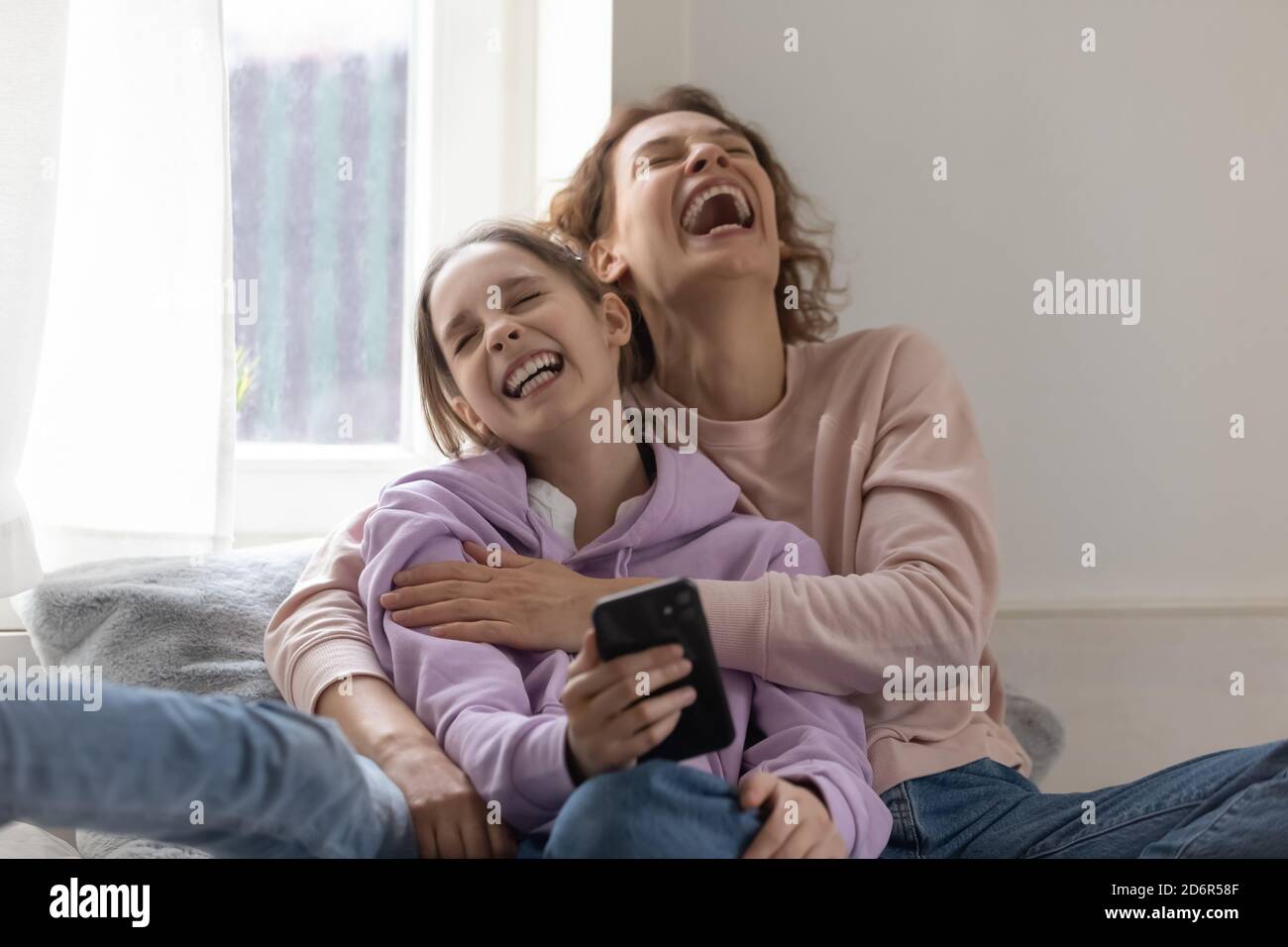 Overjoyed mother and teen daughter laugh using smartphone Stock Photo ...