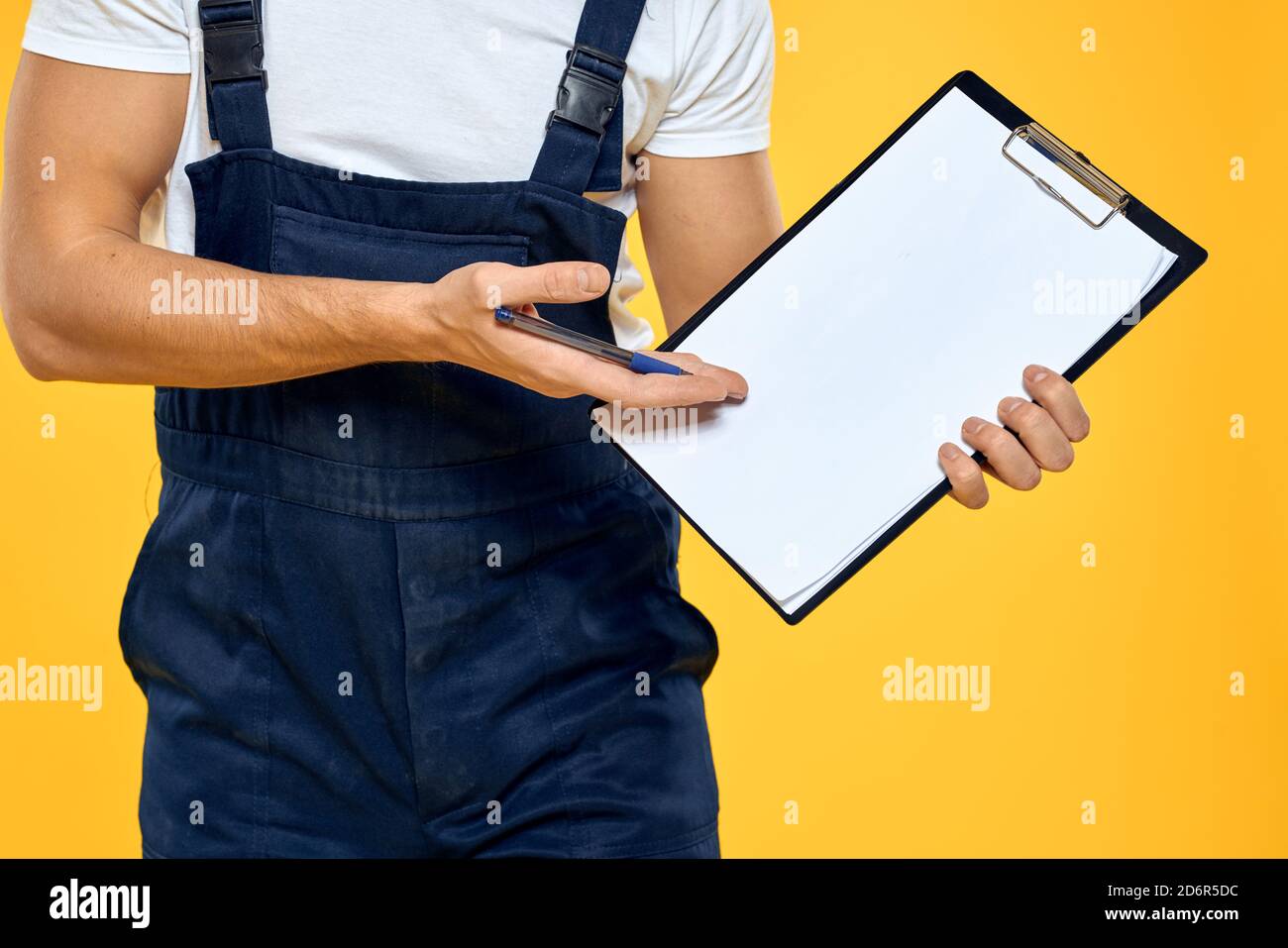 Man in working uniform documents rendering of services delivery service yellow background Stock ...