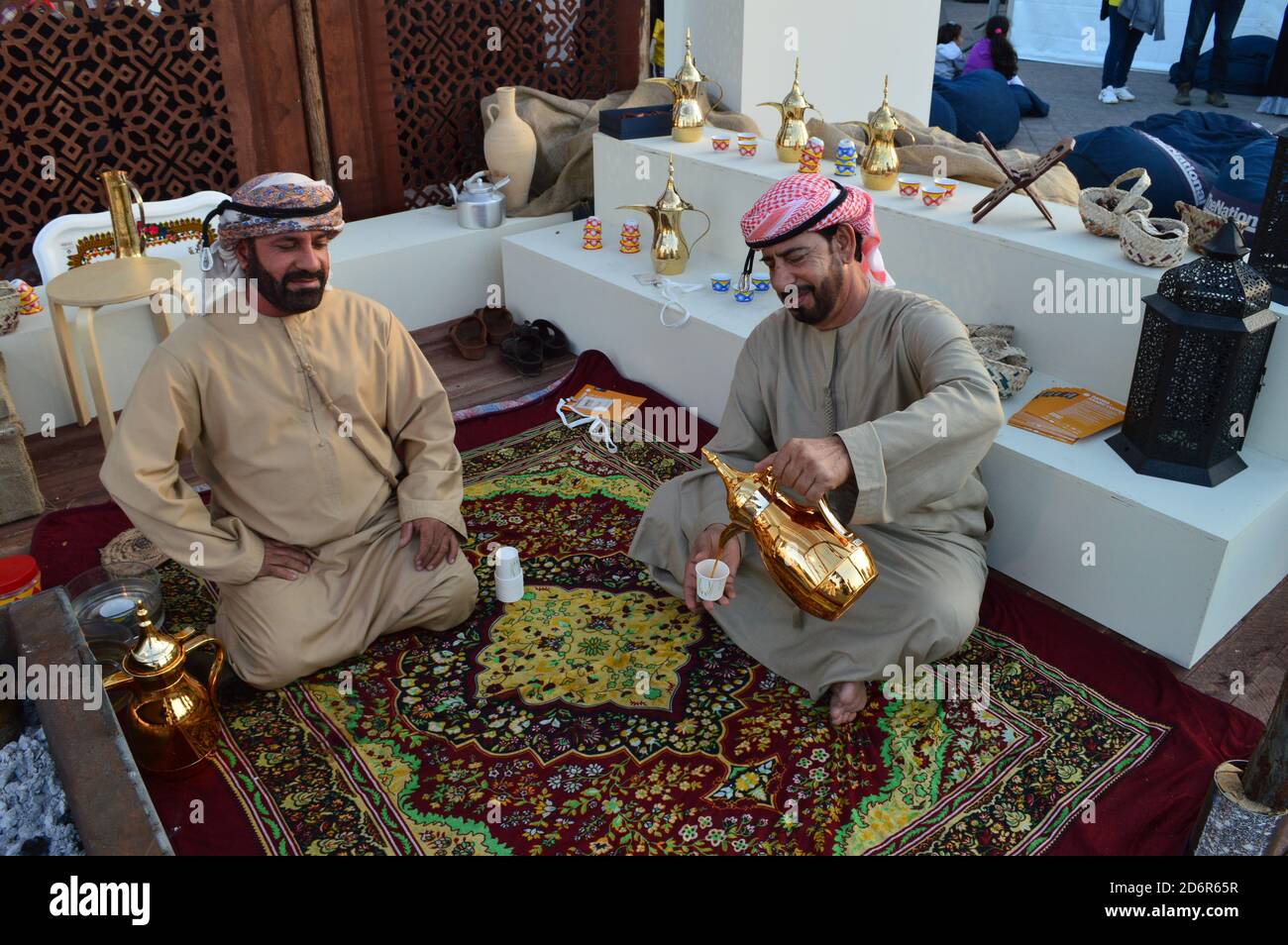 Abu Dhabi, UAE - 2019. Two Arabic men dressed traditionally, drinking ...